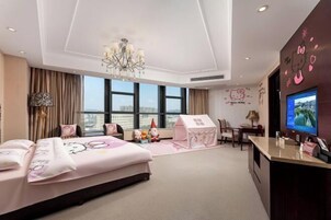 Quarto de hotel com uma cama grande, uma escrivaninha, televisão e vista para a cidade.