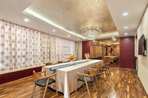 Uma sala de conferências com uma mesa comprida, cadeiras e um candelabro.