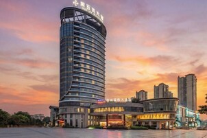 Um hotel moderno com fachada curva, vários andares e uma área de entrada destacada com sinalização.