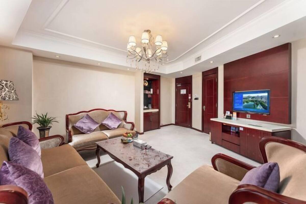 Uma sala de estar espaçosa com uma televisão grande, assentos confortáveis, um candelabro e design moderno.