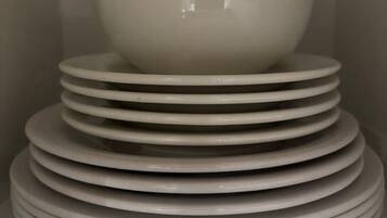 Uma pilha de pratos e tigelas brancas dentro de um armário.