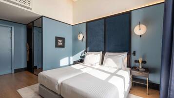 Quarto moderno com uma cama grande, uma mesa de cabeceira e uma luminária na parede.