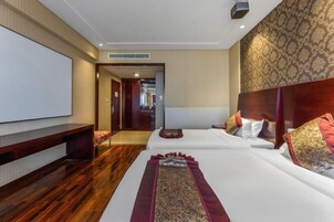 Quarto de hotel com duas camas, televisão de tela plana, um banco de madeira e parede estampada.
