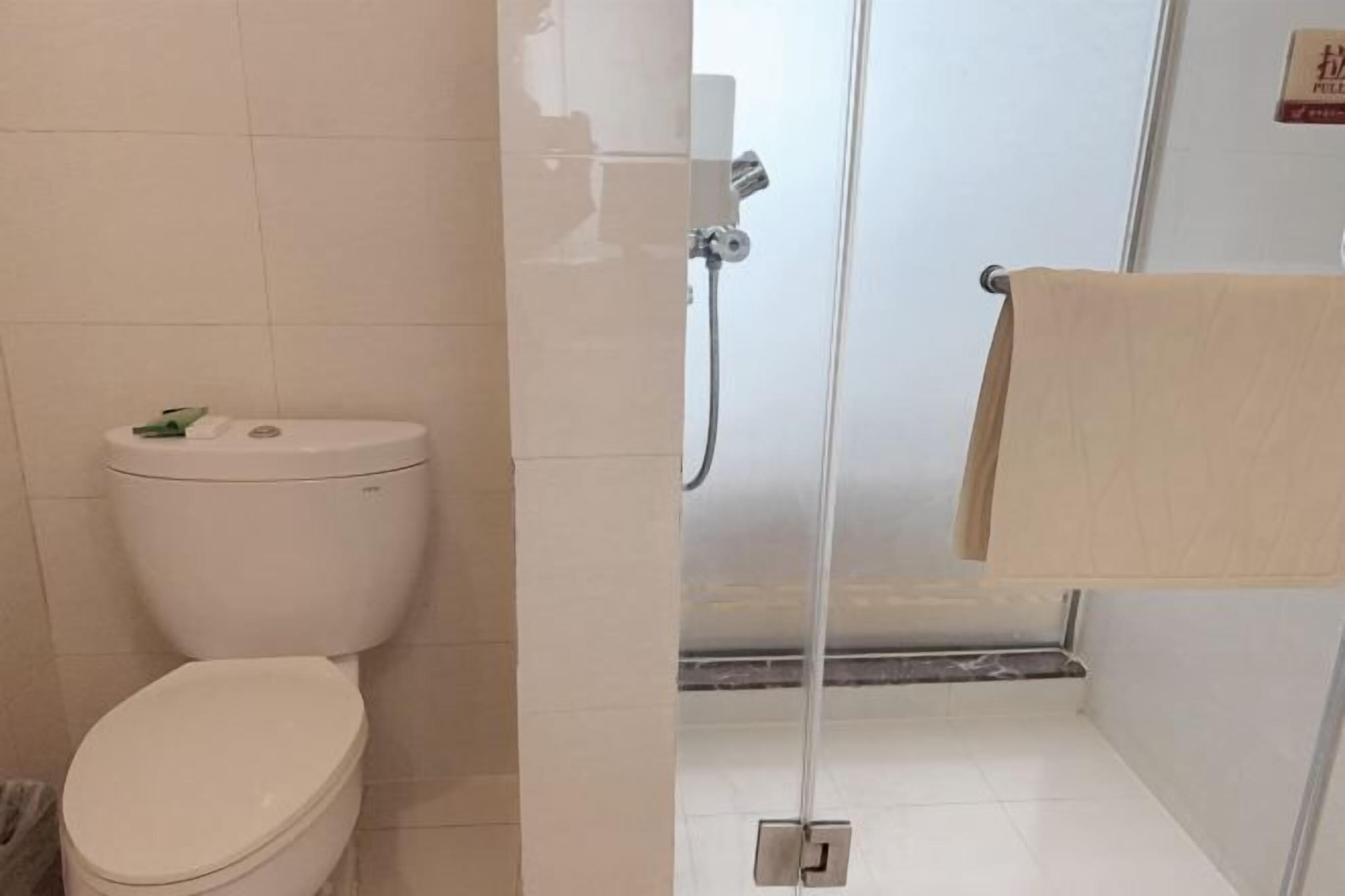 Um banheiro com vaso sanitário, box de chuveiro e porta-toalhas.