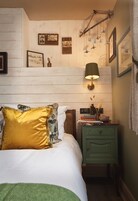 Quarto com cama, mesa de cabeceira, abajur e decorações na parede.