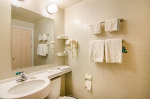 Casa de banho com lavatório, espelho, porta-toalhas e secador de cabelo.