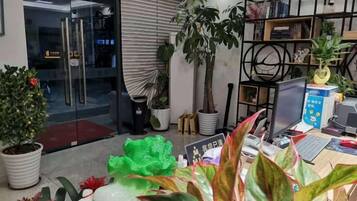 Quarto com escrivaninha, computador e vários vasos de plantas.