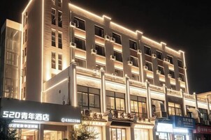Um hotel de vários andares com fachada moderna, sinalização iluminada e entrada visível.
