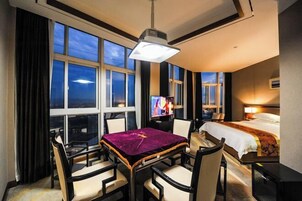 Quarto de hotel com área de refeições, uma cama e uma televisão.
