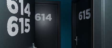 Corredor com portas identificadas pelos números 614 e 615, com algarismos grandes e padrão listrado.