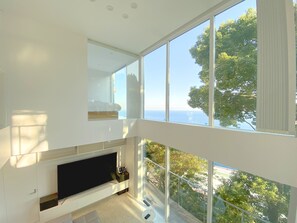 Uma sala de estar moderna com uma televisão de tela plana grande, um sofá e um espaço de jantar.