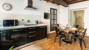 Uma cozinha moderna com armários pretos, micro-ondas e uma mesa de jantar com cadeiras.