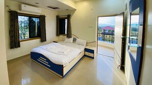 Quarto com cama, ventilador de teto, aparelhos de ar condicionado e vista para uma varanda com guarda-corrimão.