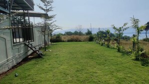 Um gramado com um edifício à esquerda e vista para montanhas ao longe.