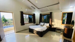 Quarto espaçoso com uma cama grande, mesa de cabeceira, ar condicionado e vista para o exterior pela janela.