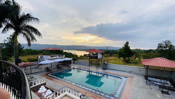 Área da piscina com vista para montanhas e um lago.