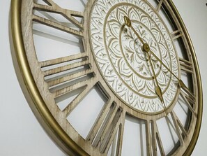 Um close-up de um relógio decorativo com números romanos e desenhos elaborados.