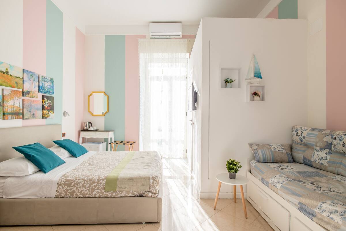 Quarto com cama, sofá, mesa pequena e escrivaninha.
