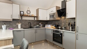 Uma cozinha moderna com armários cinza, micro-ondas, forno e máquina de café.