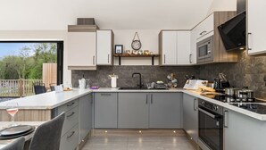 Uma cozinha moderna com armários cinzentos, forno embutido, micro-ondas e uma grande ilha com pia.
