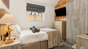 Quarto com cama, abajur e televisão montada na parede.