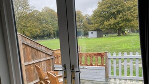 Visão através de uma porta de vidro para um espaço de pátio externo com cerca de madeira, cerca branca de piquete e gramado.