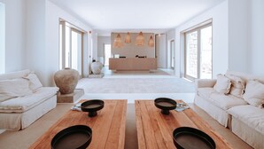 Um amplo saguão de hotel com balcão de recepção, janelas grandes e design minimalista.
