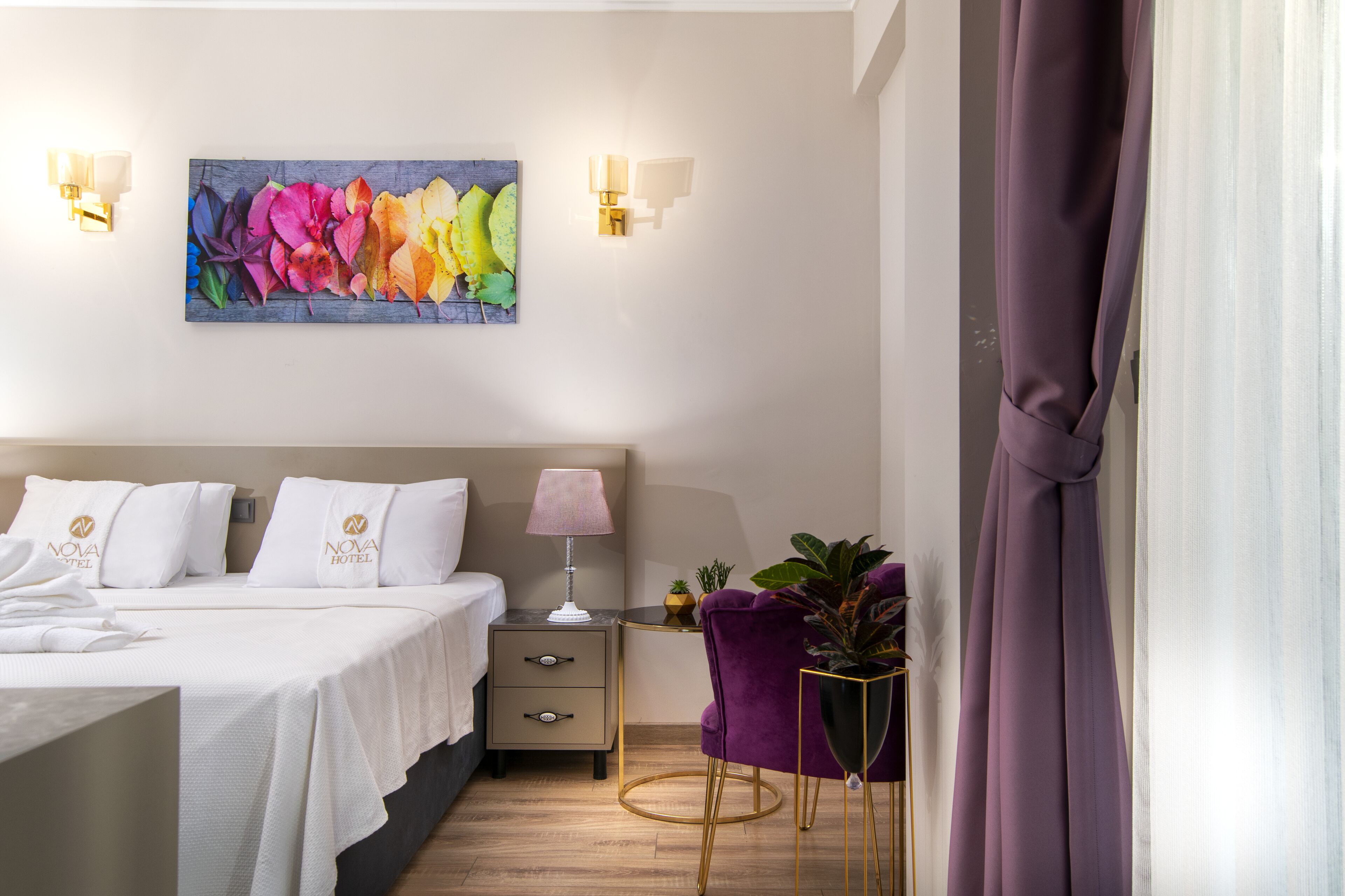 Quarto de hotel com cama, mesas de cabeceira, abajur, cadeira e um quadro na parede.