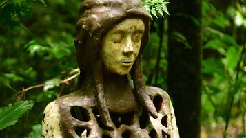 Uma escultura com detalhes em baixos-relevos, emoldurada por uma vegetação densa.