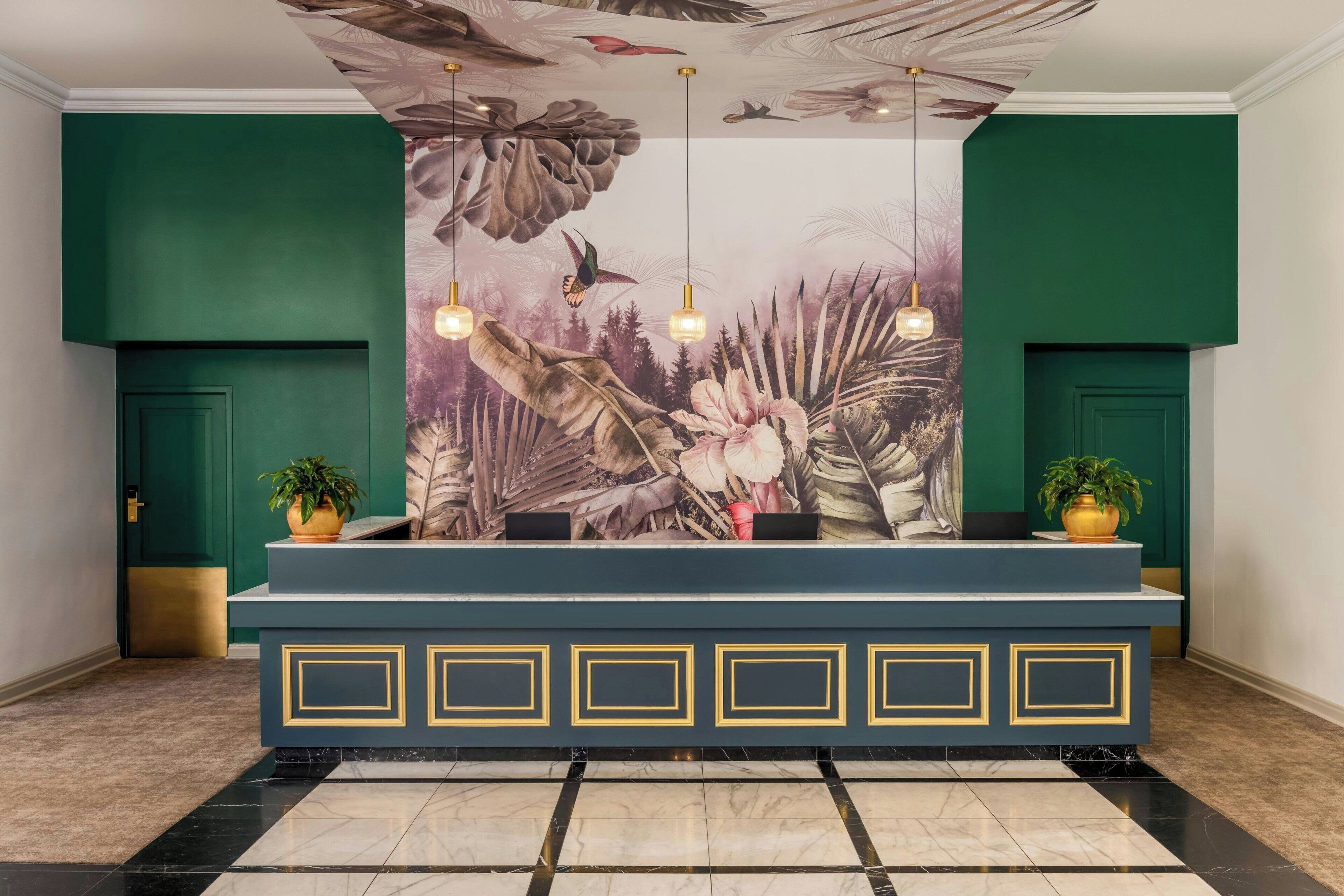 Uma receção com um mural floral, paredes verdes e chão de mármore.