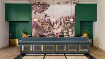 Uma receção com um mural floral, paredes verdes e chão de mármore.