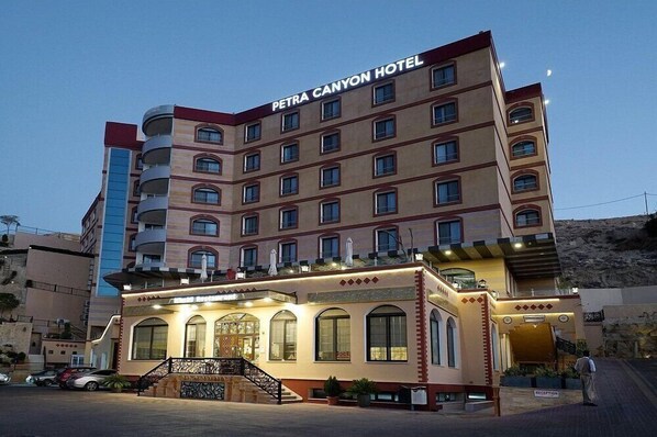 Um hotel de vários andares com entrada marcante, varandas e céu claro.