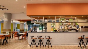 Uma área de bar moderna com diversas opções de assento, incluindo banquetas e mesas.
