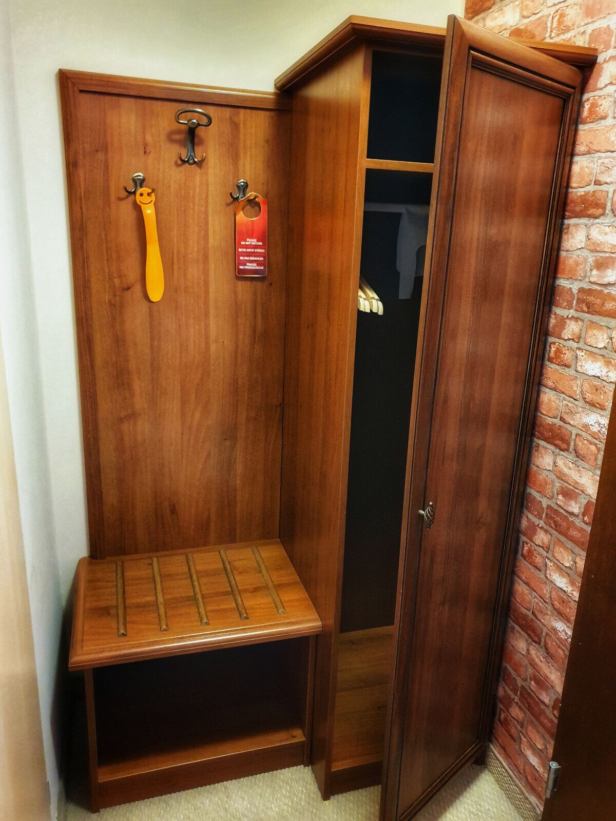 Um guarda-roupa de madeira com um banco, um espelho e uma placa vermelha.