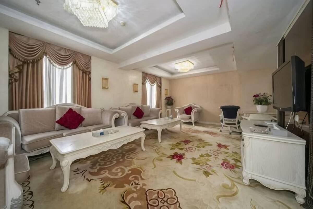 Uma sala de estar ampla, com sofá, mesa de centro, TV e tapete decorativo.