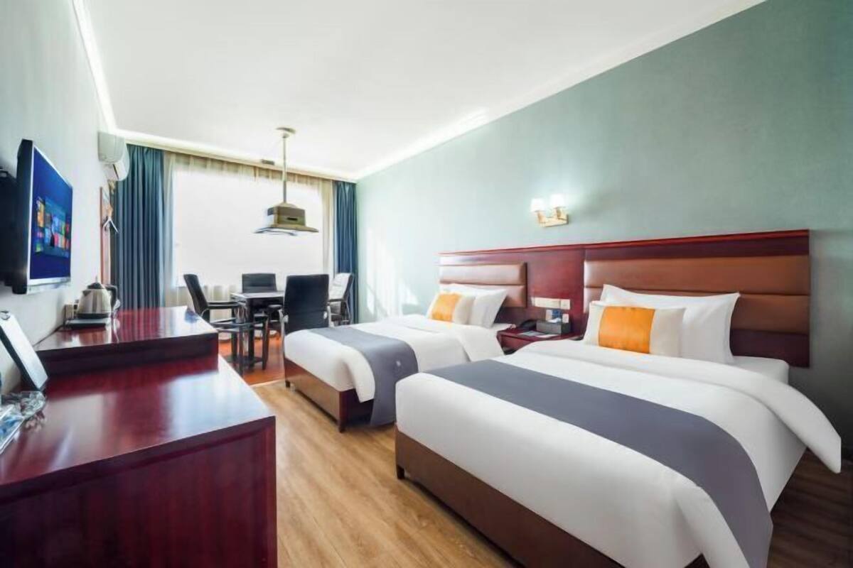 Quarto de hotel com duas camas, uma escrivaninha e uma televisão.
