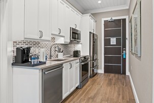 Cozinha moderna com armários brancos, eletrodomésticos de aço inoxidável e painel de backsplash de tijolo.