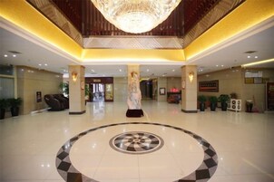 Um saguão de hotel com design circular central, um candelabro e um balcão de recepção.
