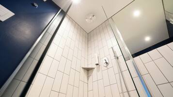 Um banheiro moderno com azulejos brancos, box de vidro e uma parede azul decorativa.
