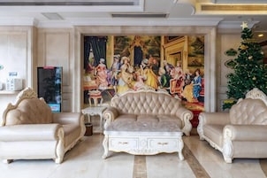 Uma sala de estar luxuosa com um grande mural, uma árvore de Natal e móveis ricamente decorados.