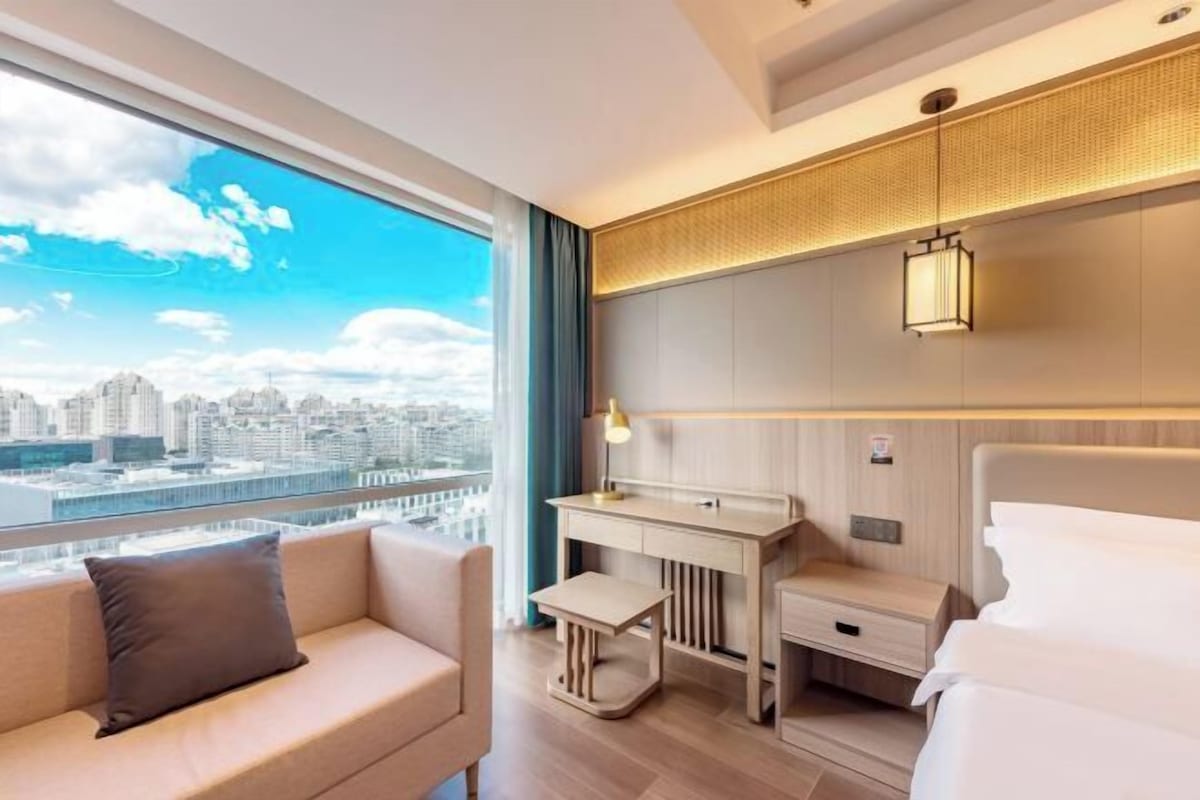 Quarto de hotel moderno com vista para a cidade, um sofá, uma escrivaninha e uma cama.