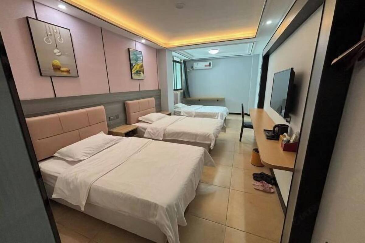 Quarto de hotel com duas camas, uma mesa, televisão e obras de arte nas paredes.
