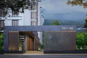 Entrada moderna de um hotel com uma placa de destaque, uma cobertura e vista da região ao redor.