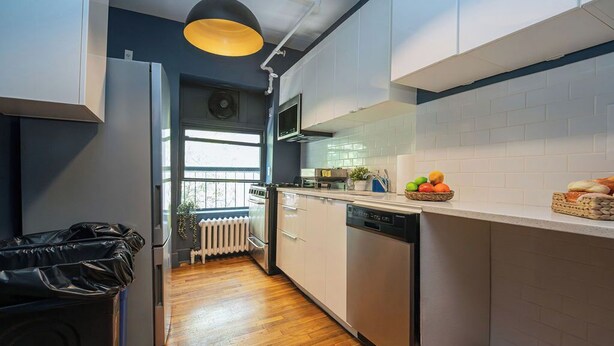 Uma cozinha moderna com armários brancos, máquina de lavar louça e janela com vista.