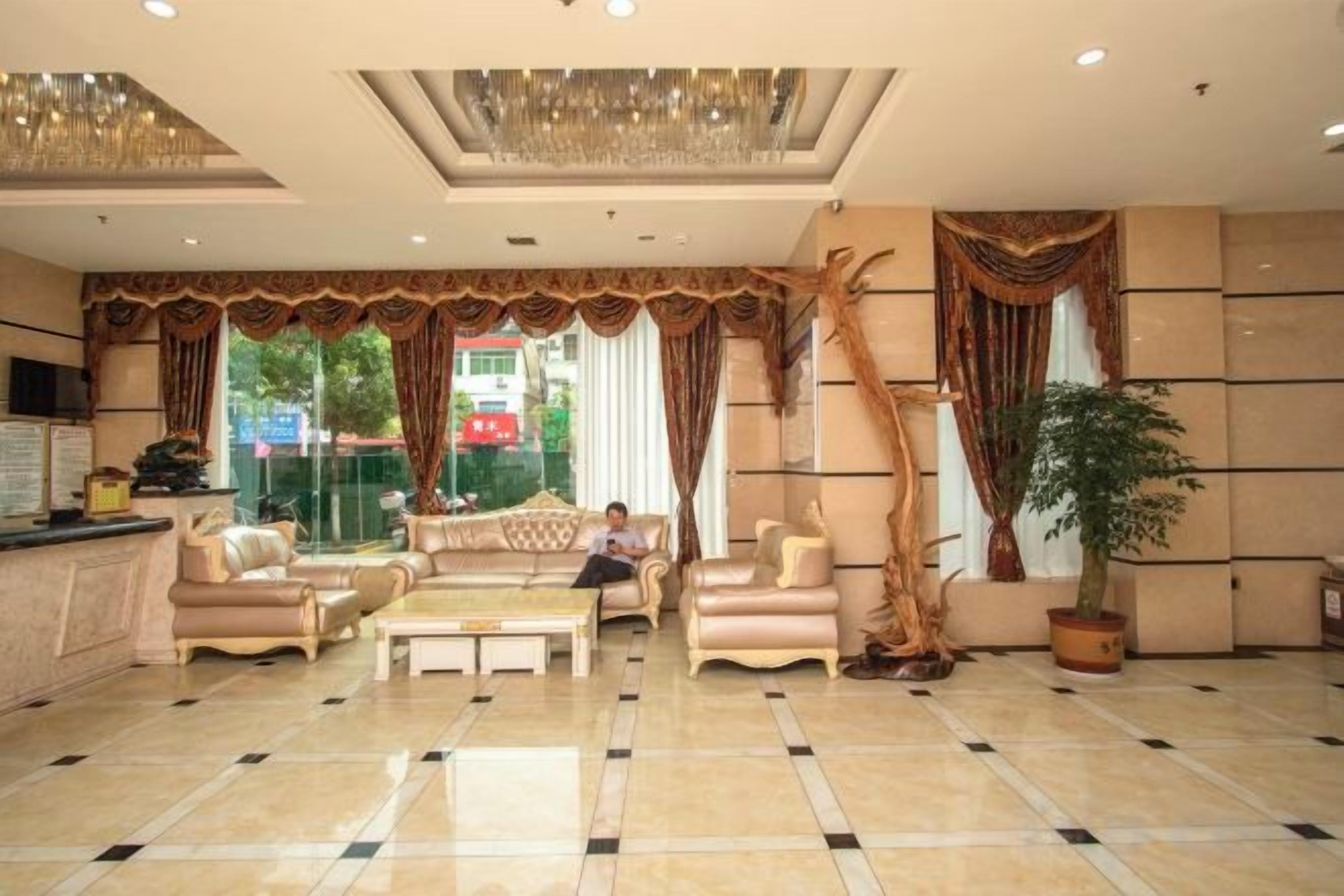 Um hall amplo com balcão de recepção, assentos confortáveis e uma planta grande.