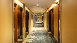 Corredor de hotel com portas de madeira, carpete estampado e extintor de incêndio.