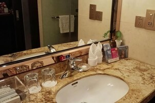 Casa de banho com lavatório de mármore, espelho, porta-toalhas e produtos de higiene pessoal.