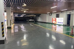 Garagem de estacionamento com setas de direção claras no chão, ambiente limpo e bem iluminado e uma porta de saída visível.