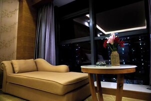 Um quarto com sofá, uma mesa redonda e um vaso com flores.