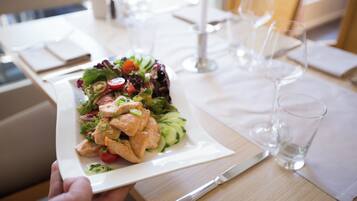 Prato branco com salada e frango sobre uma mesa de madeira.